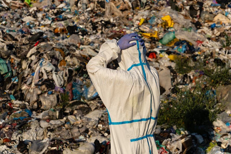 A Worker in a Protective Suit Surveys a Vast Landfill Filled with ...