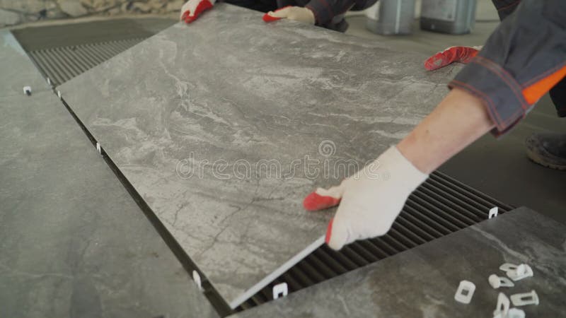 Workers are Laying the Floor with Large Tiles. a Worker Puts a Large ...