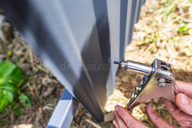 A Worker Puts Rivets into a Profiled Sheet on a Fence. Stock Image ...