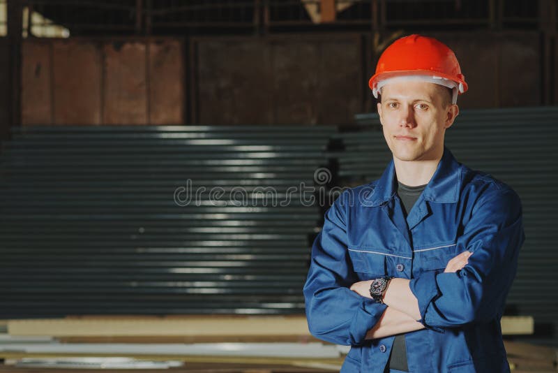 Worker in a Red Cap and Uniform Stands Against the Backdrop of T Stock ...