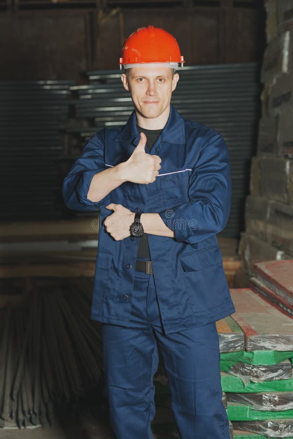 Worker in a Red Cap and Uniform Stands Against the Backdrop of T Stock ...
