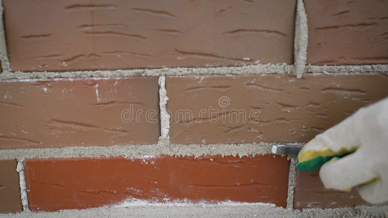 A Worker Rubbing Seams on a Brick Wall while Building a House. Grouting ...