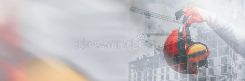 A Worker in Safety Gloves Holds an Orange Hard Hat Against a ...