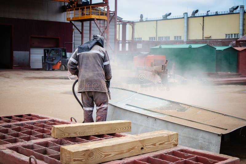 A Worker Sandblasting a Metal Structure To Remove Rust at an Industrial ...