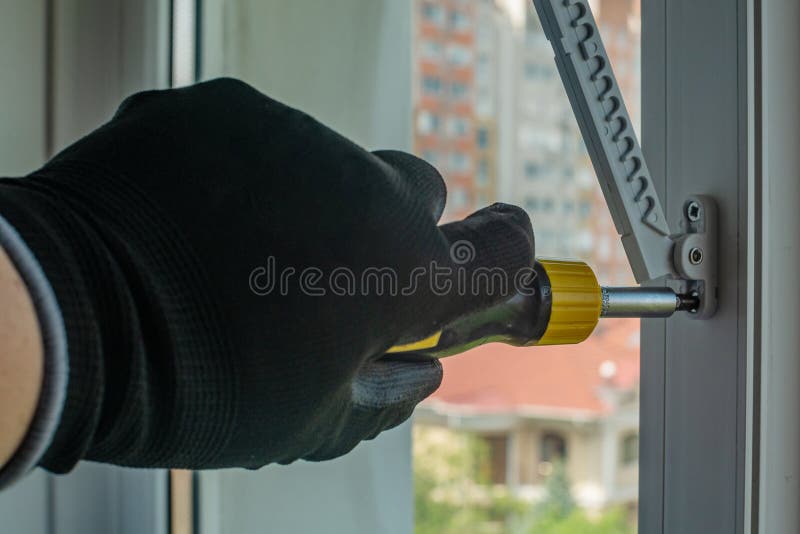 The Worker with a Screwdriver Screws the Fixing into the Window Frame ...