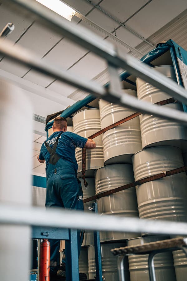 Worker Seen from a Low Angle Pushing Multiple Barrels of Goods Along a ...