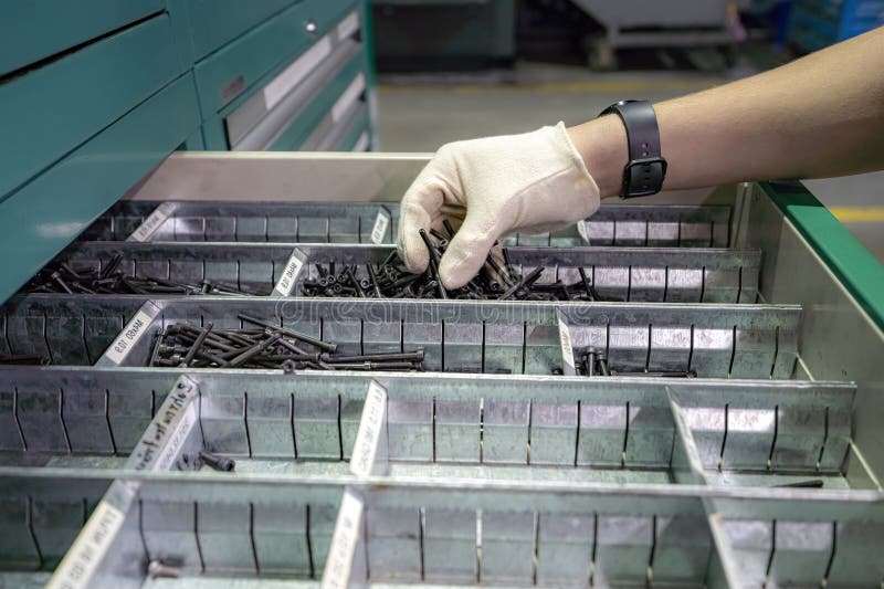 A Worker Selects Bolts and Nuts for Work from a Box of Hardware Stock ...