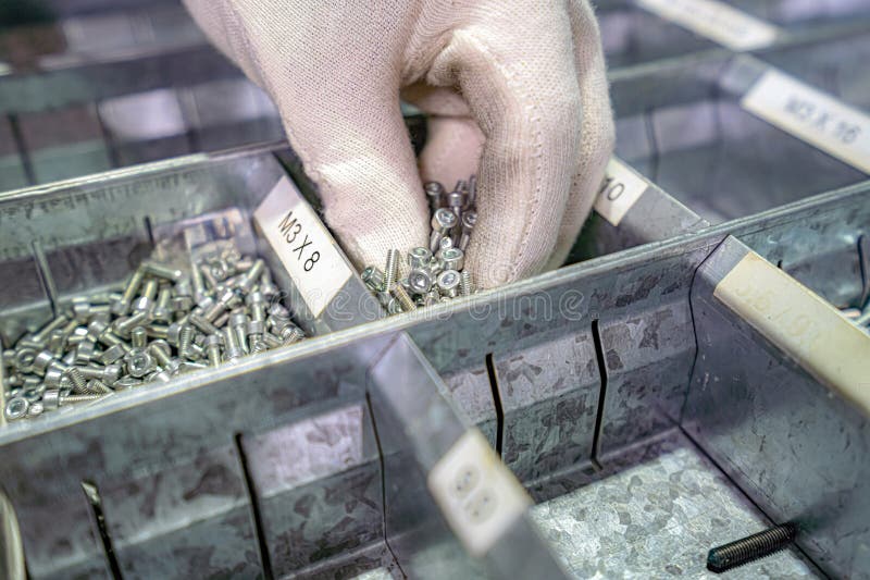 A Worker Selects Bolts and Nuts for Work from a Box of Hardware Stock ...