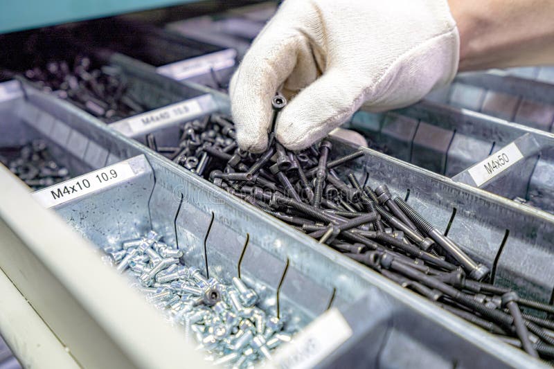 A Worker Selects Bolts and Nuts for Work from a Box of Hardware Stock ...