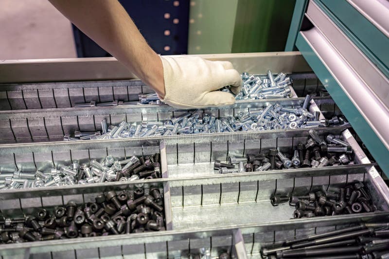 A Worker Selects Bolts and Nuts for Work from a Box of Hardware Stock ...