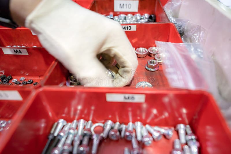 A Worker Selects Bolts and Nuts for Work from a Box of Hardware Stock ...