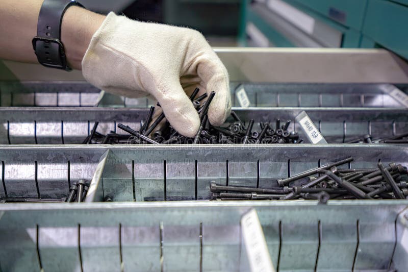 A Worker Selects Bolts and Nuts for Work from a Box of Hardware Stock ...