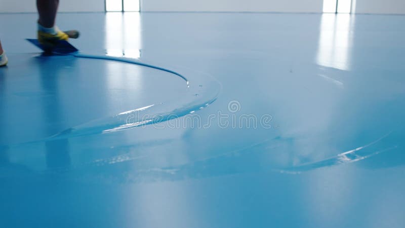 Worker Smooths a Glossy Blue Epoxy Coating Onto the Floor Using a ...