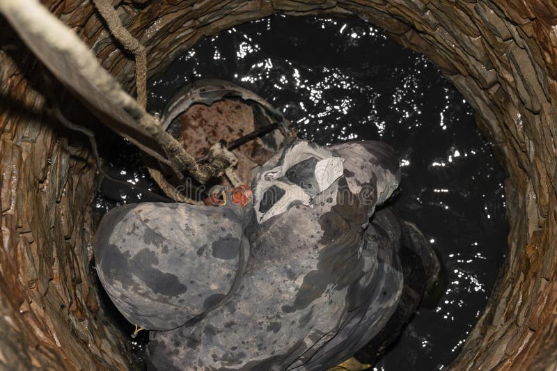 A Worker Stands at the Bottom of a Well with a Bucket into Which Water ...