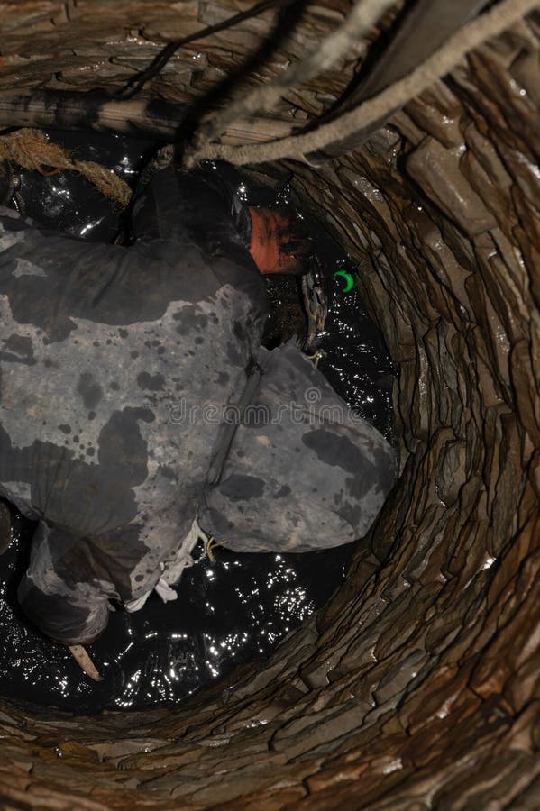 A Worker Stands at the Bottom of a Well with a Bucket into Which Water ...