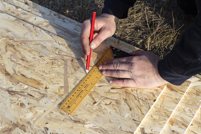 The Worker Takes Measurements and Marks on the OSB Sheet Using a Square ...