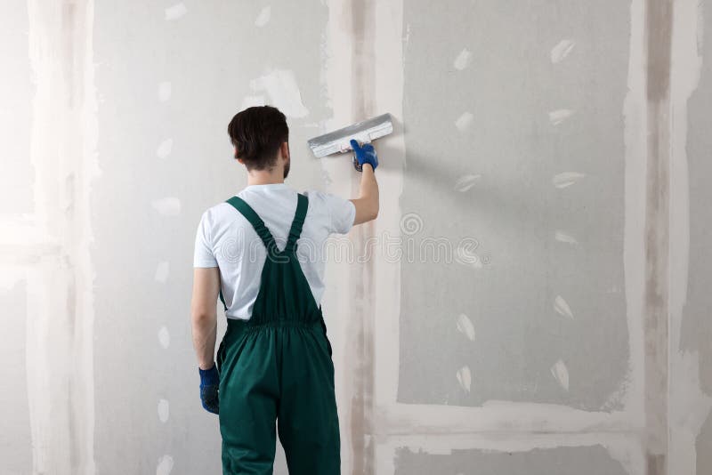 Worker in Uniform Plastering Wall with Putty Knife Indoors, Back View ...