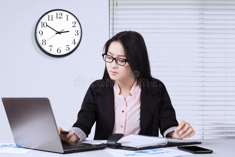 Worker Uses Laptop with Clock on the Wall Stock Photo - Image of ...