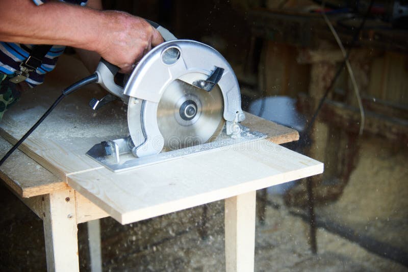 A Worker Using a Circular Saw Works with Wood in a Carpenter`s Workshop ...