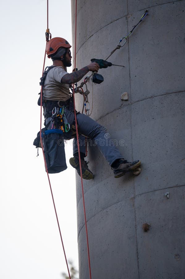 Rope Access Technician Using Cordless Drill on Concrete Chimney Stock ...