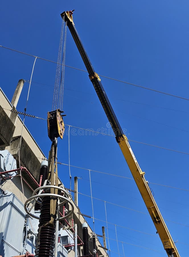 A Worker Using a Crane To Install a Large, Ceramic Electrical Insulator ...