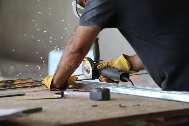 Worker Using an Electric Grinder, Viewed from Behind. Background with ...