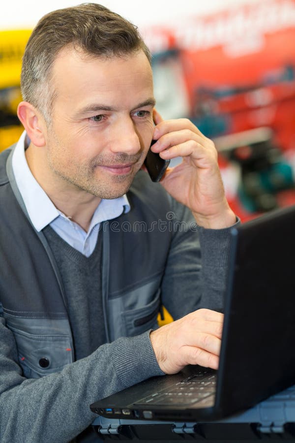 Worker Using Phone and Laptop in Store Stock Image - Image of person ...