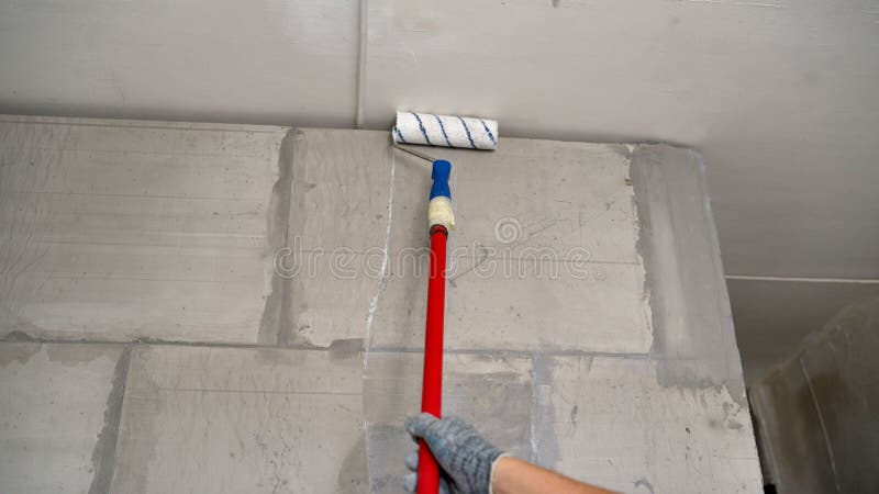 Worker Using Paint Roller To Paint the Wall. Prime the Wall Using a ...
