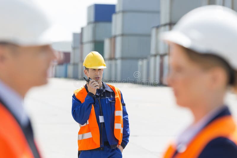 Worker Using Walkie-talkie while Colleagues Discussing in Foreground at ...
