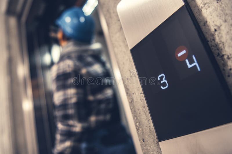 Worker Waiting for Elevator Near Display Showing Floors in a Modern ...