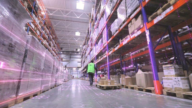 The Worker Walks through the Warehouse. a Worker is Carrying a Rokla ... The Worker Walks through the Warehouse. a Worker is Carrying a Rokla ...