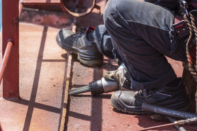 Worker Wearing Gloves Uses a Pneumatic Tool To Remove Rust from a Metal ...