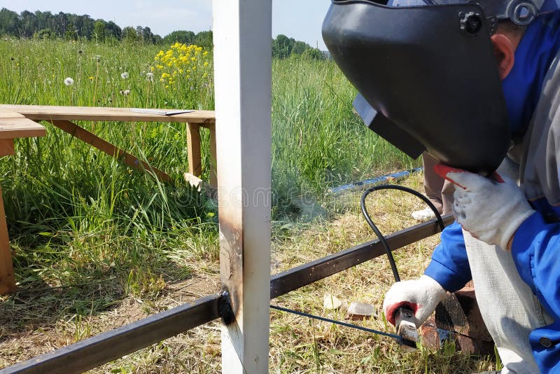 Worker with Welding Machine Welds the Fence Around the House Stock ...
