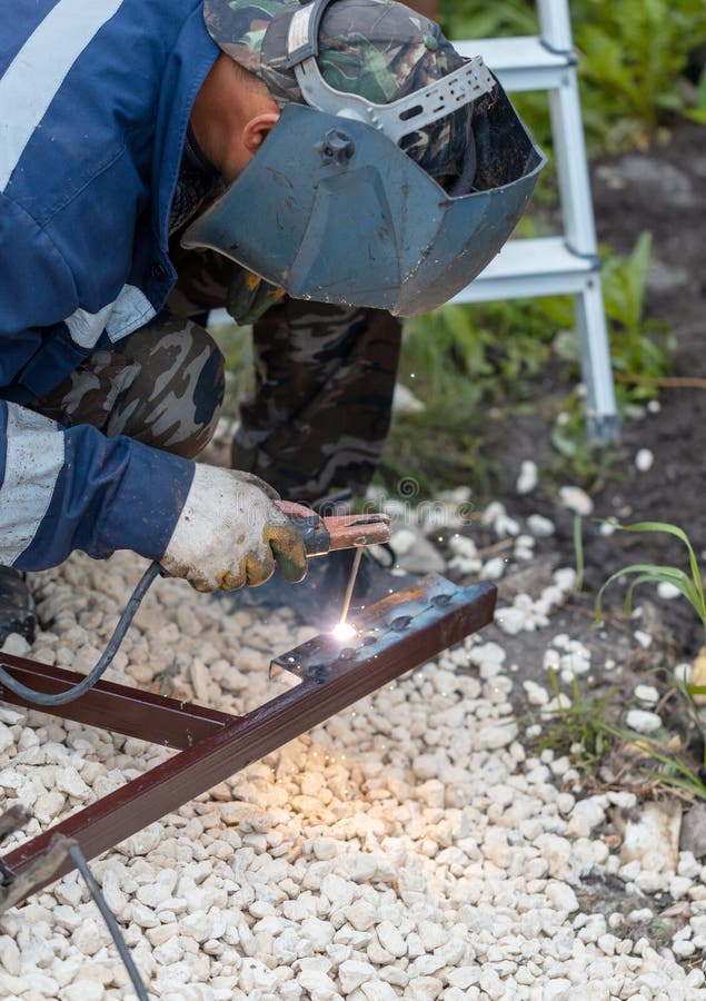 A Worker Welds Metal at a Construction Site. Stock Image - Image of ...