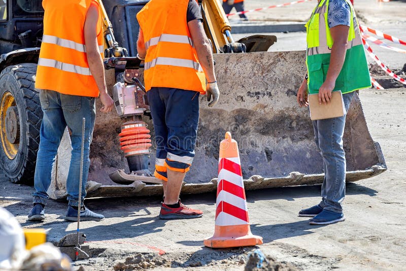 Workers in Bright Vests Operate Machinery at a Construction Site Under ...