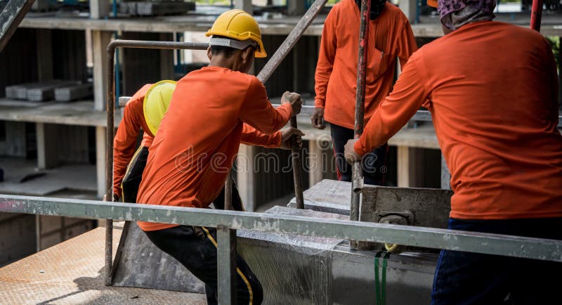 Workers at a Building Under Construction Take Slabs from a Crane Stock ...