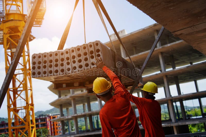 Workers at a Building Under Construction Take Slabs from a Crane Stock ...