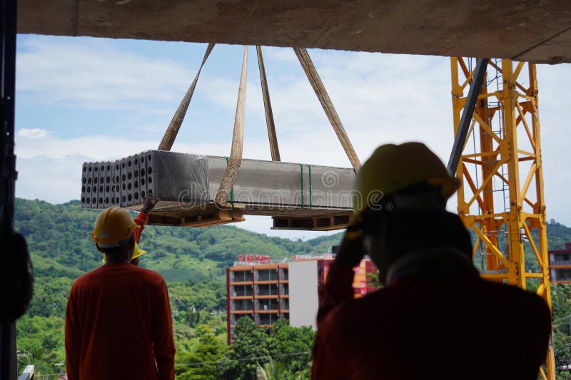 Workers at a Building Under Construction Take Slabs from a Crane Stock ...