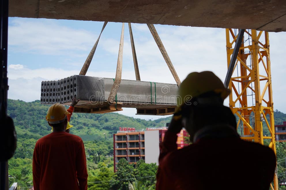 Workers at a Building Under Construction Take Slabs from a Crane Stock ...