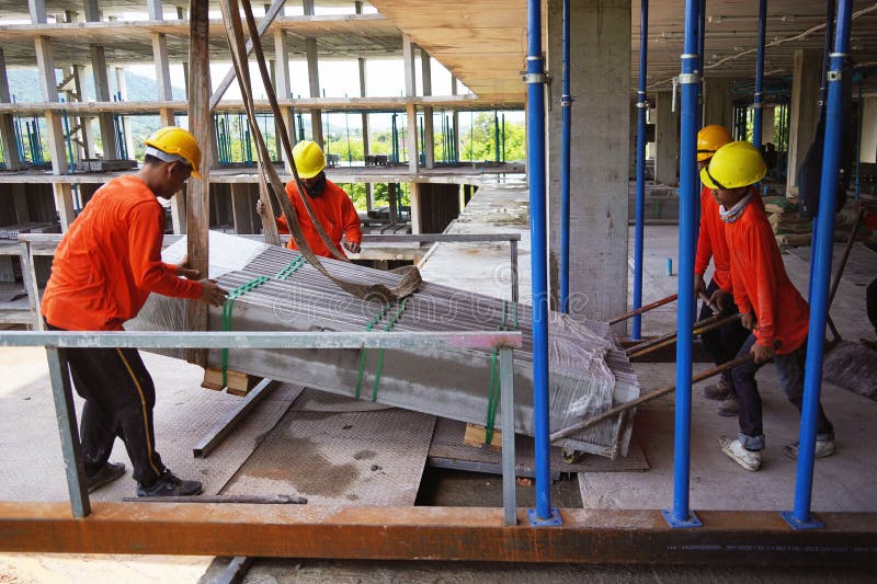 Workers at a Building Under Construction Take Slabs from a Crane Stock ...