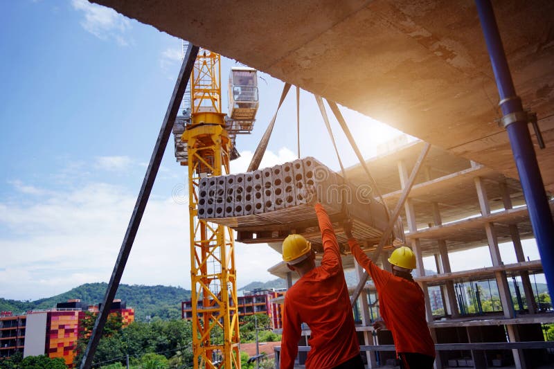 Workers at a Building Under Construction Take Slabs from a Crane Stock ...