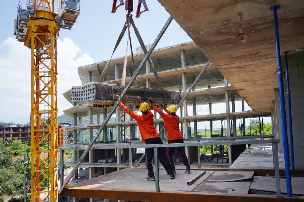 Workers at a Building Under Construction Take Slabs from a Crane Stock ...
