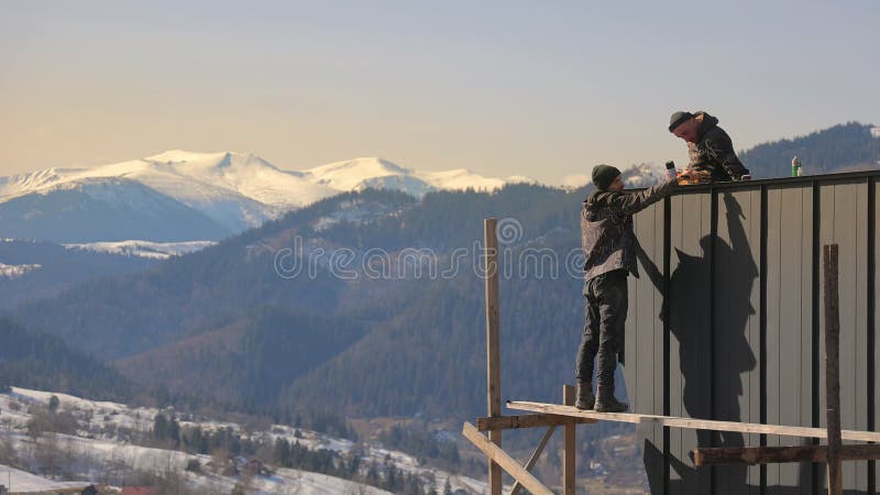 Workers Constructing a Modern Rooftop, Scenic Winter Mountains with ...