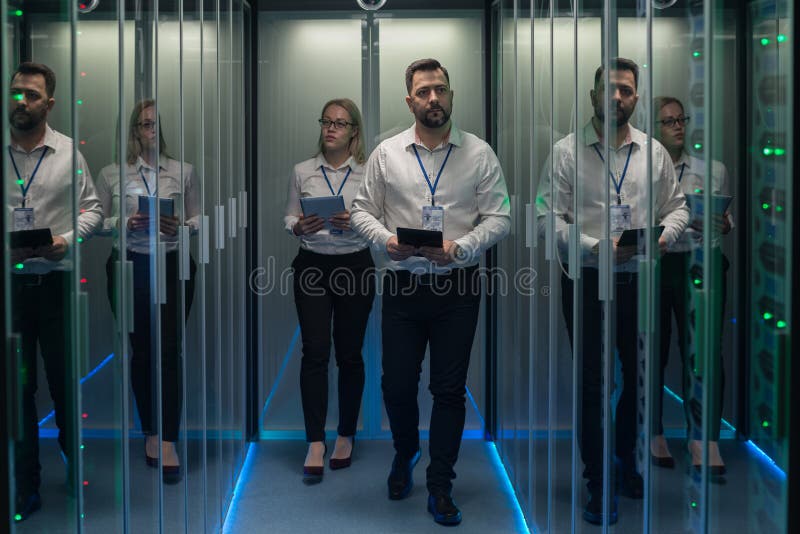 Workers in a Data Center Walking between Rows of Server Racks Stock ...