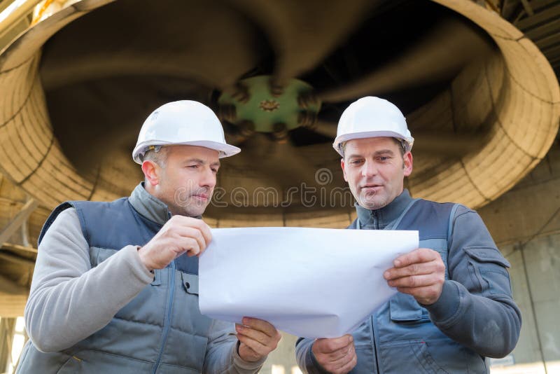 Workers Discussing Paperwork on Construction Site Stock Image - Image ...