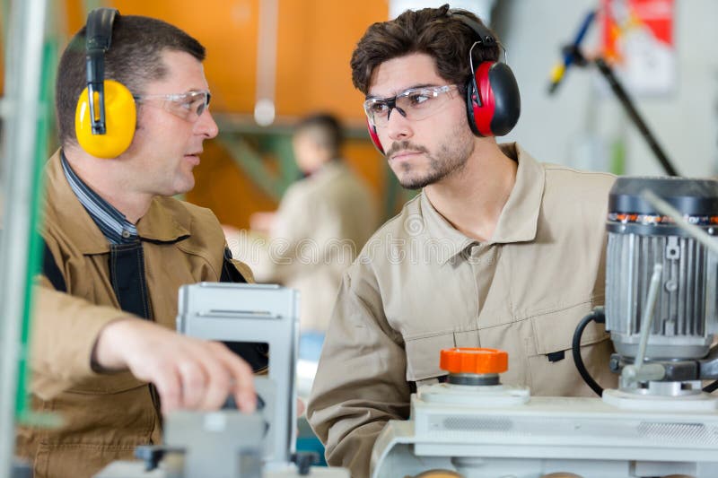 Workers with Earmuffs and Goggles Operating Machine Stock Photo - Image ...
