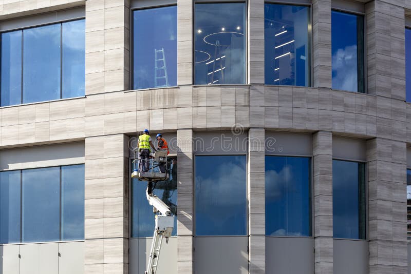 Workers in Elevated Platform Cleaning Building Facade Window Glass ...
