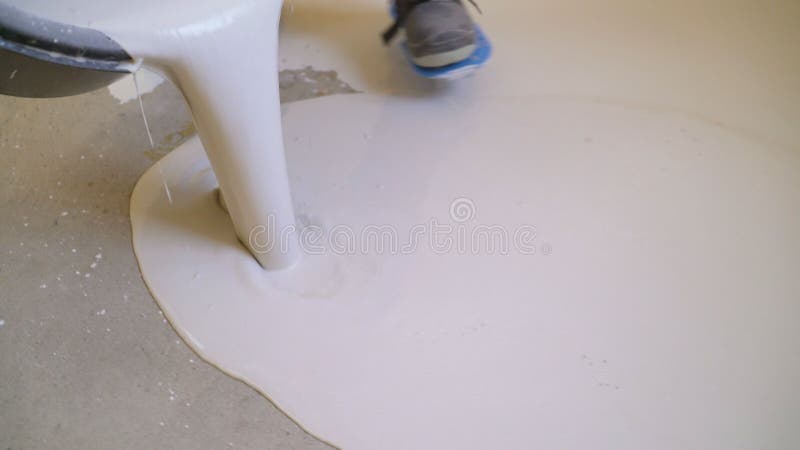 Workers Flood the Floor. Liquid Flooring. Leveling the Floor with a ...