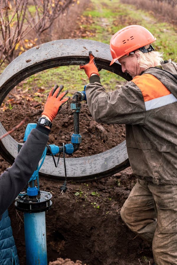 Workers Install a Water Intake Unit in a Well. Installation of the ...