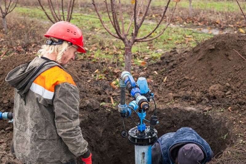 Workers Install a Water Intake Unit in a Well. Installation of the ...